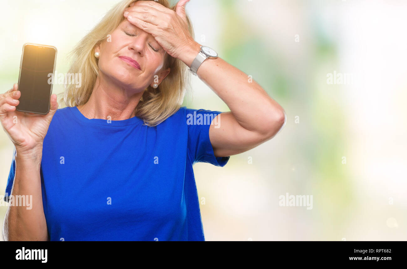 Middle age blonde woman showing blank screen of smartphone over ...