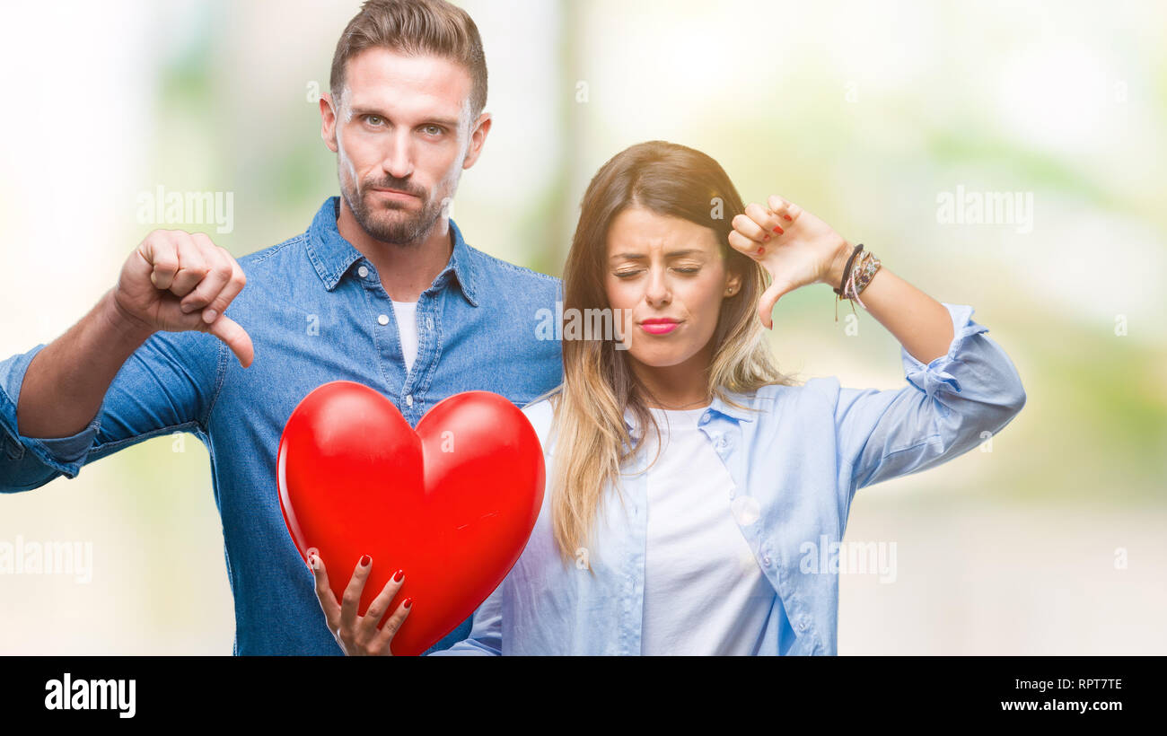 Young couple in love holding red heart over isolated background with ...