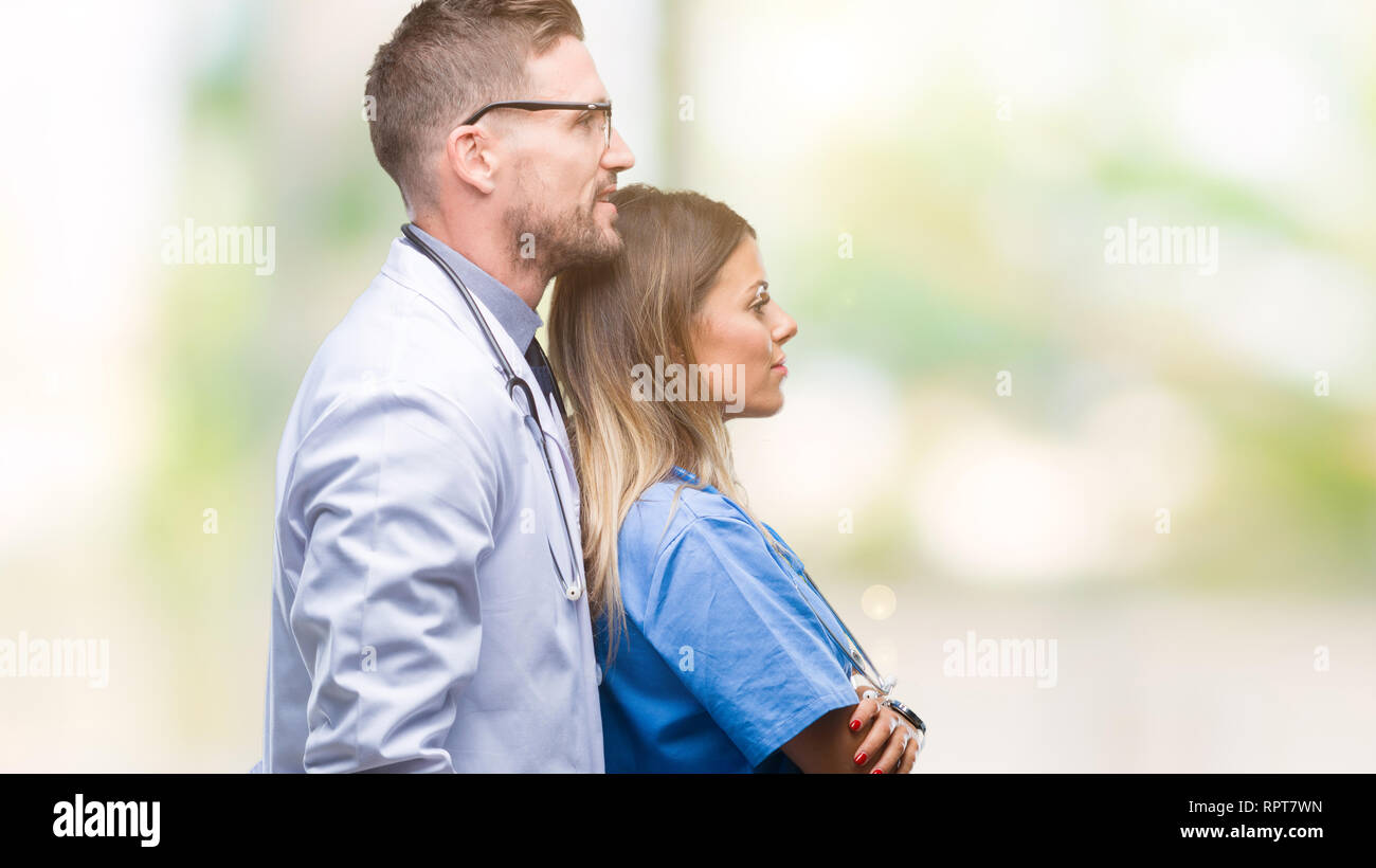 Young couple of doctor and surgeon over isolated background looking to ...