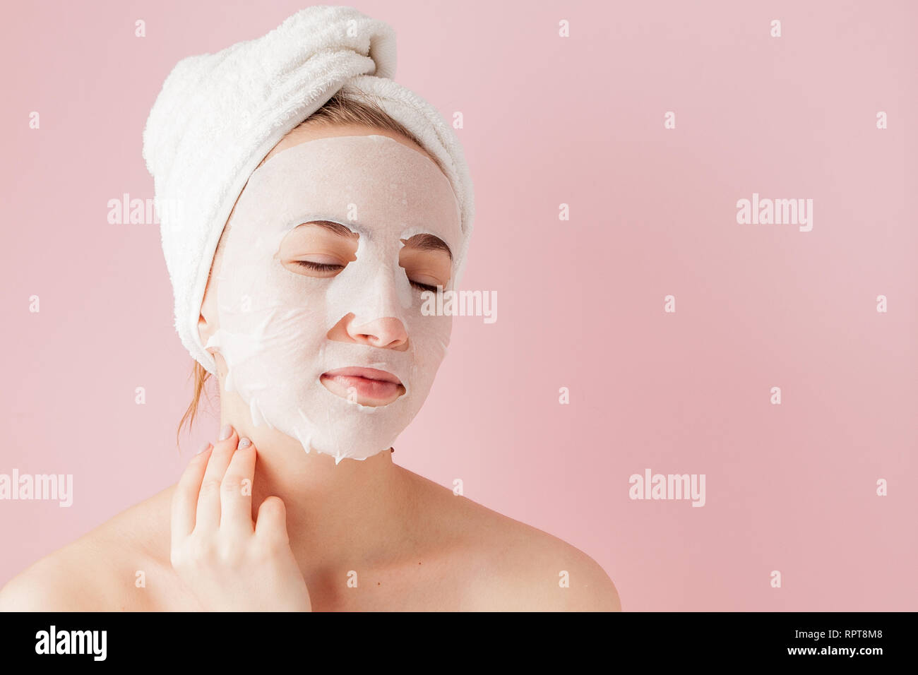 Beautiful young woman is applying a cosmetic tissue mask on a face on a ...