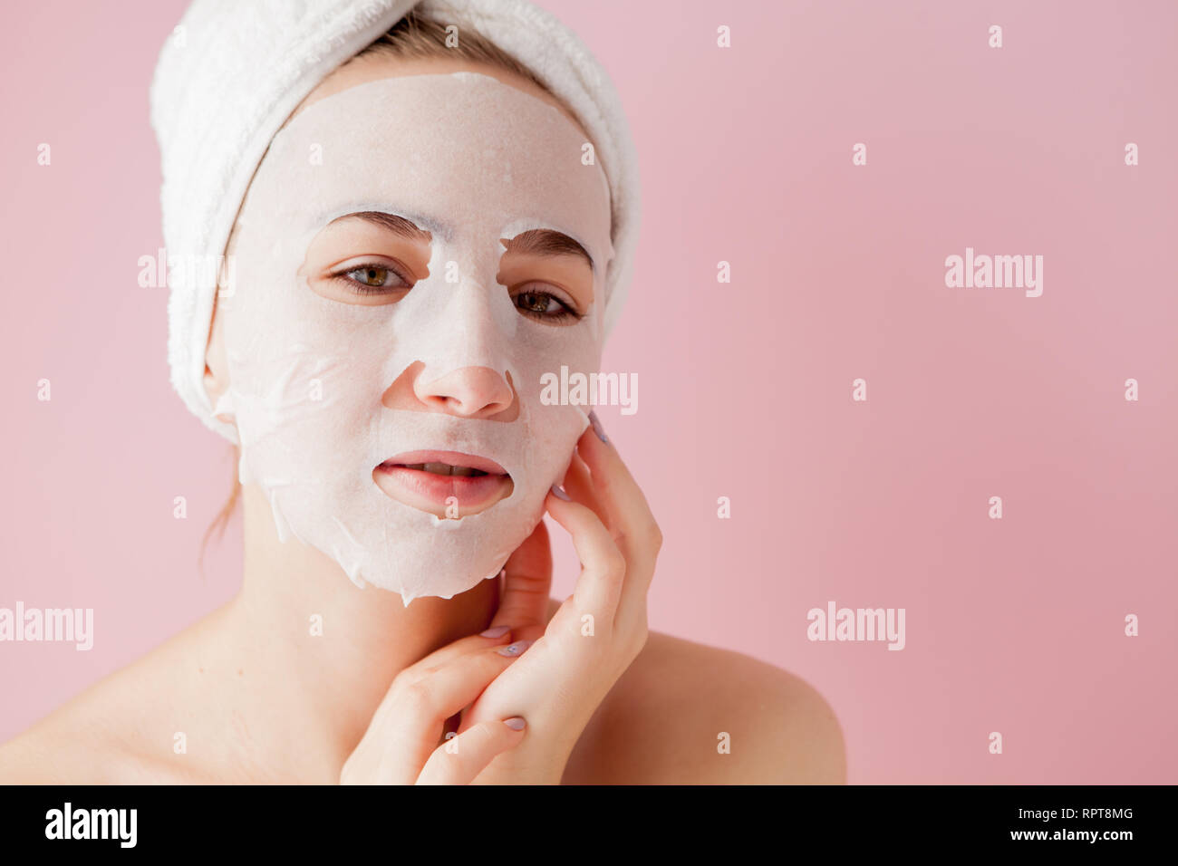 Beautiful young woman is applying a cosmetic tissue mask on a face on a ...