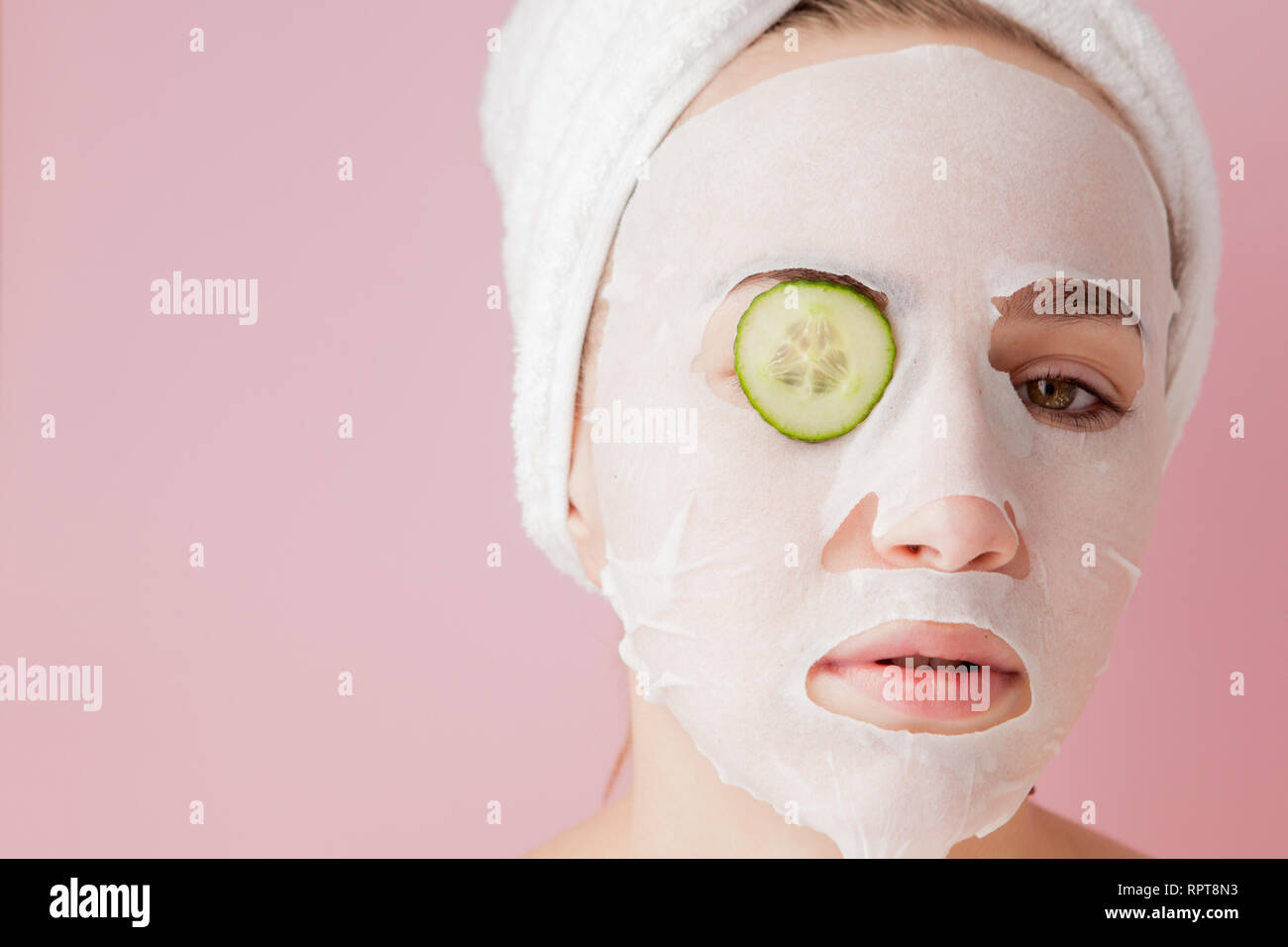 Beautiful young woman is applying a cosmetic tissue mask on a face with ...