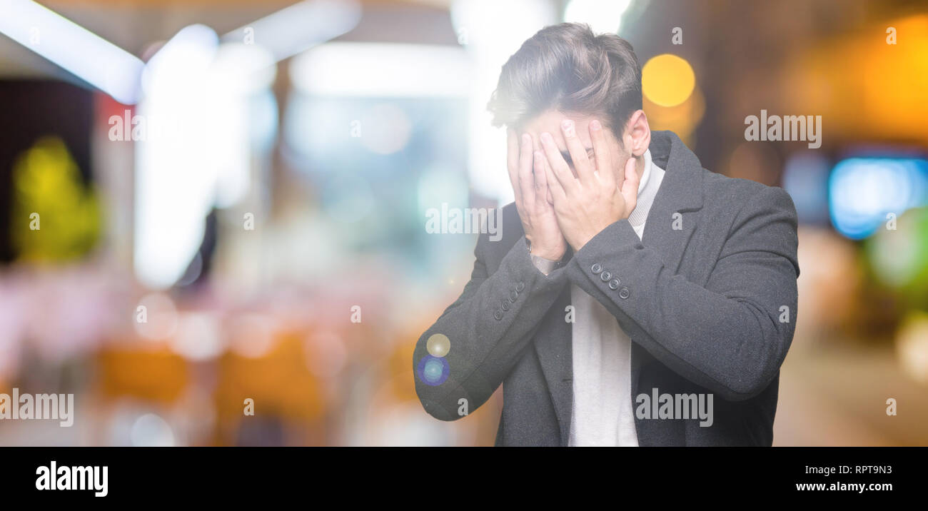 Young elegant man wearing winter coat over isolated background with sad ...
