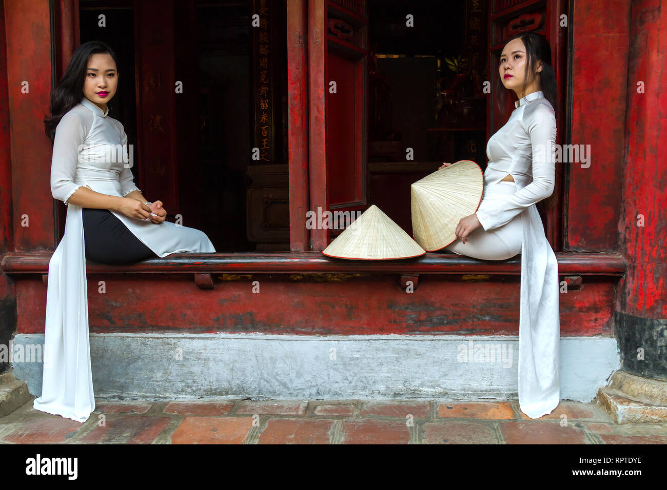Young Vietnamese women wearing the traditional dress Ao Dai and the conical hat Non La. Location ...