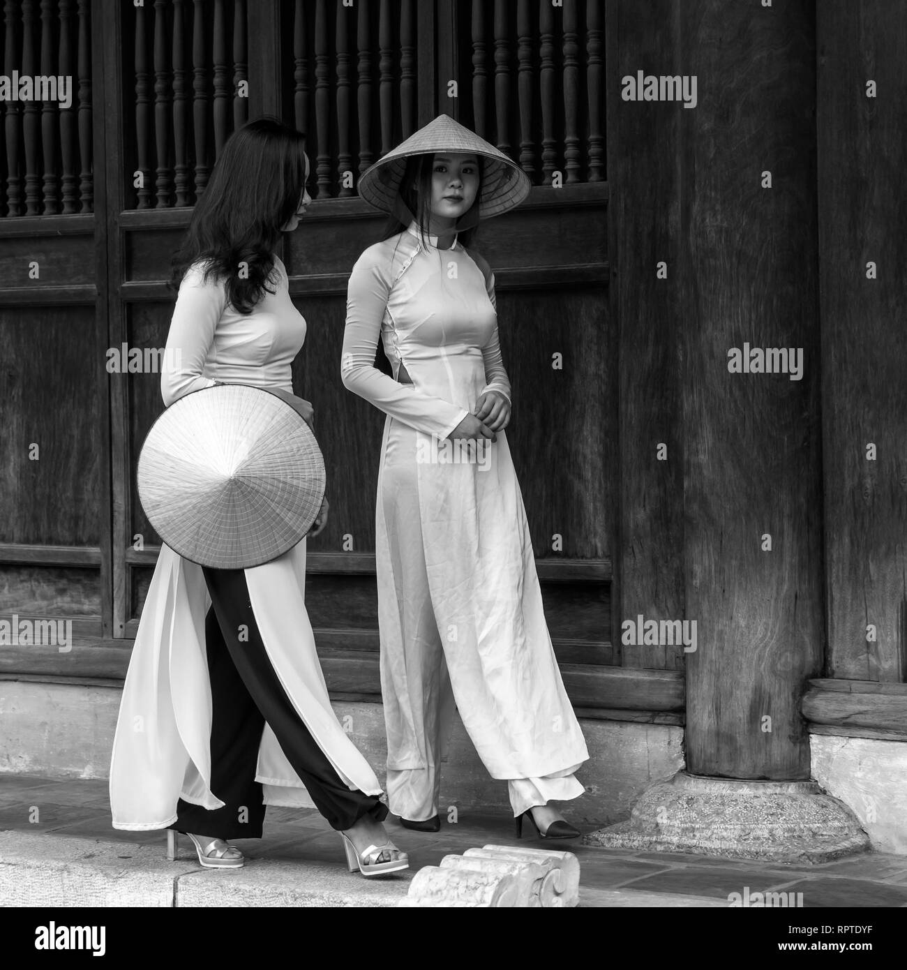 Young Vietnamese women wearing the traditional dress Ao Dai and the conical hat Non La. Location ...
