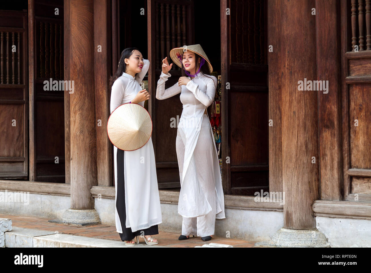 Young Vietnamese women wearing the traditional dress Ao Dai and the conical hat Non La. Location ...