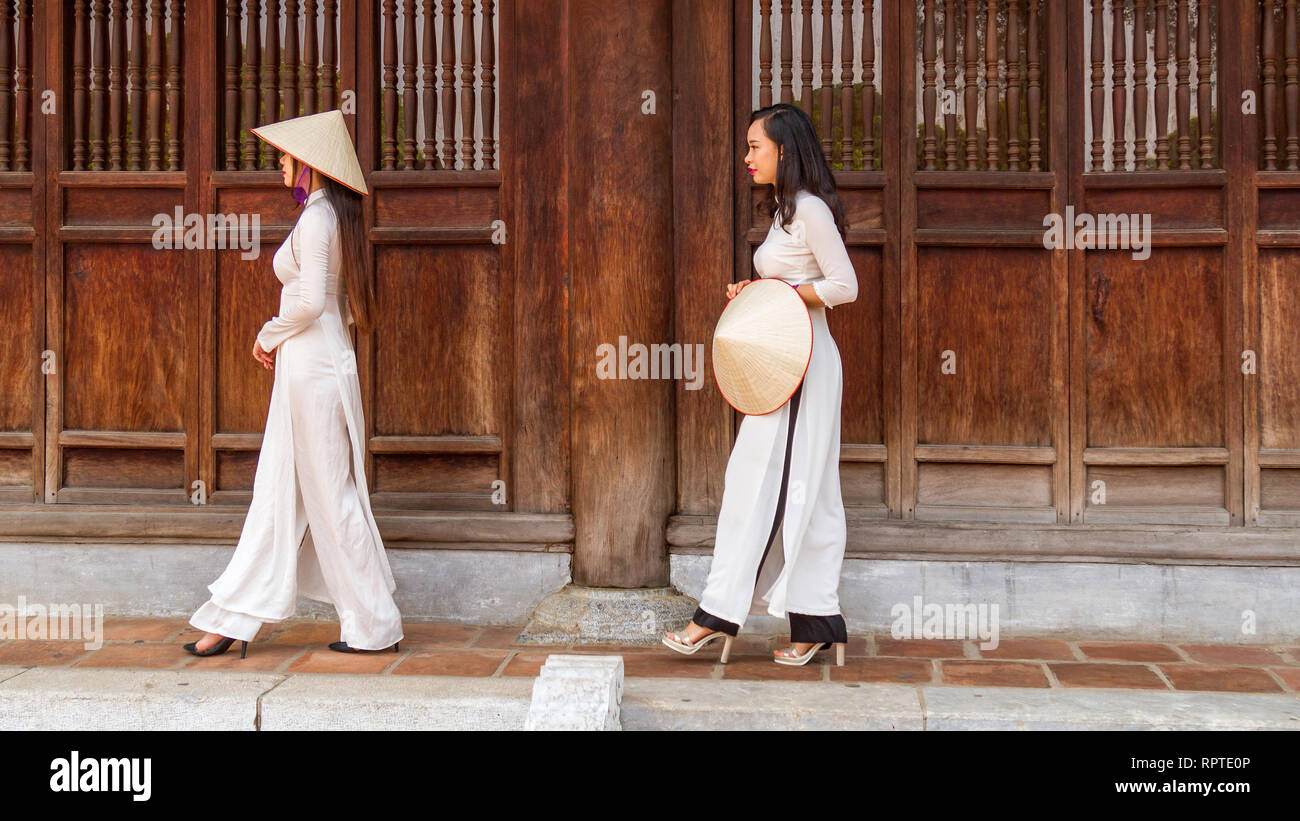 Young Vietnamese women wearing the traditional dress Ao Dai and the conical hat Non La. Location ...