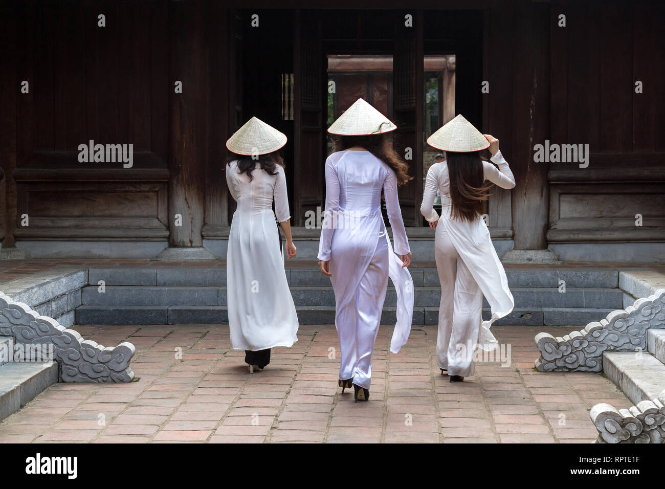 Young Vietnamese women wearing the traditional dress Ao Dai and the conical hat Non La. Location ...