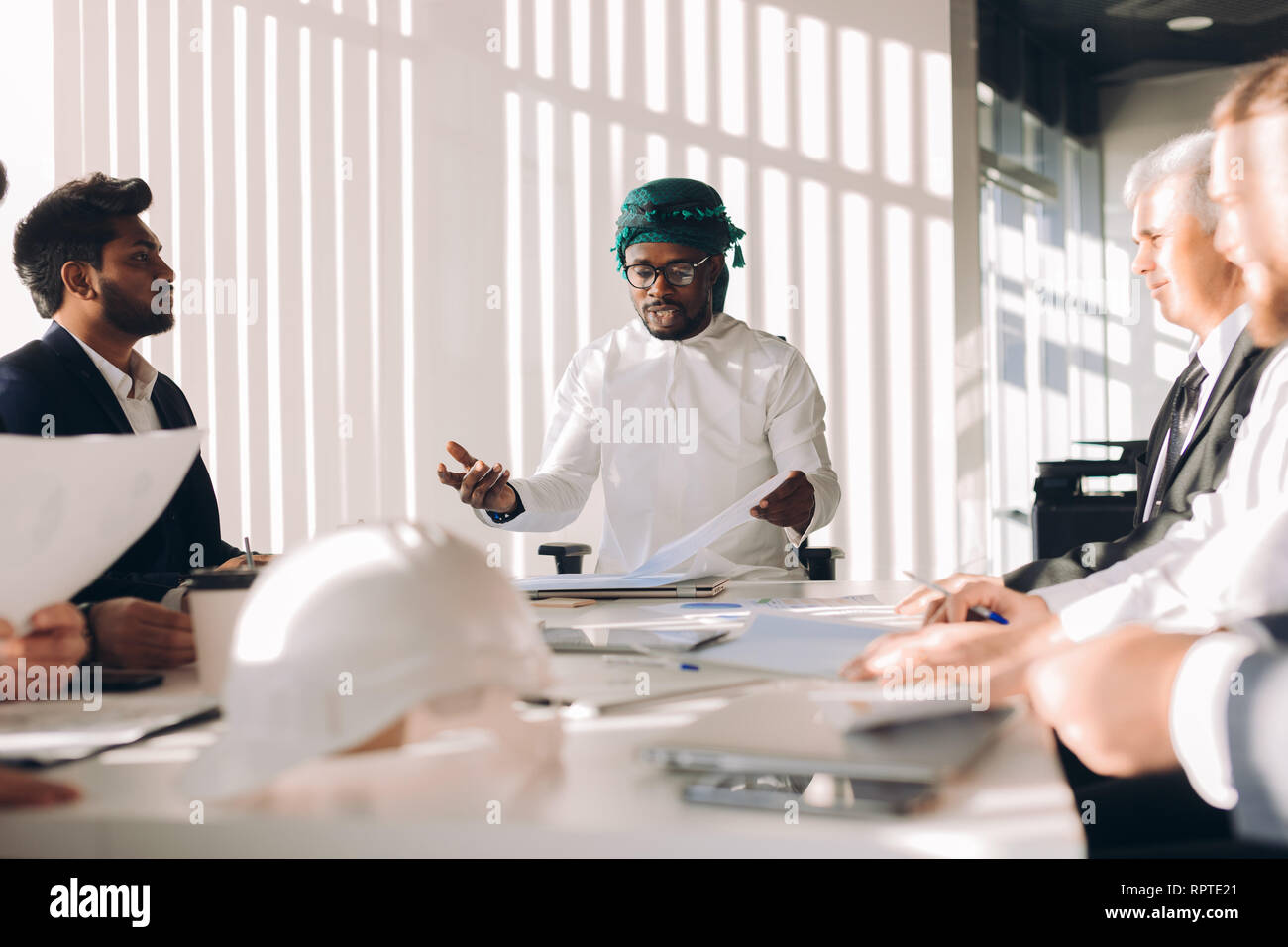 Arabian investor in white national candura and gutra on head discussing ...