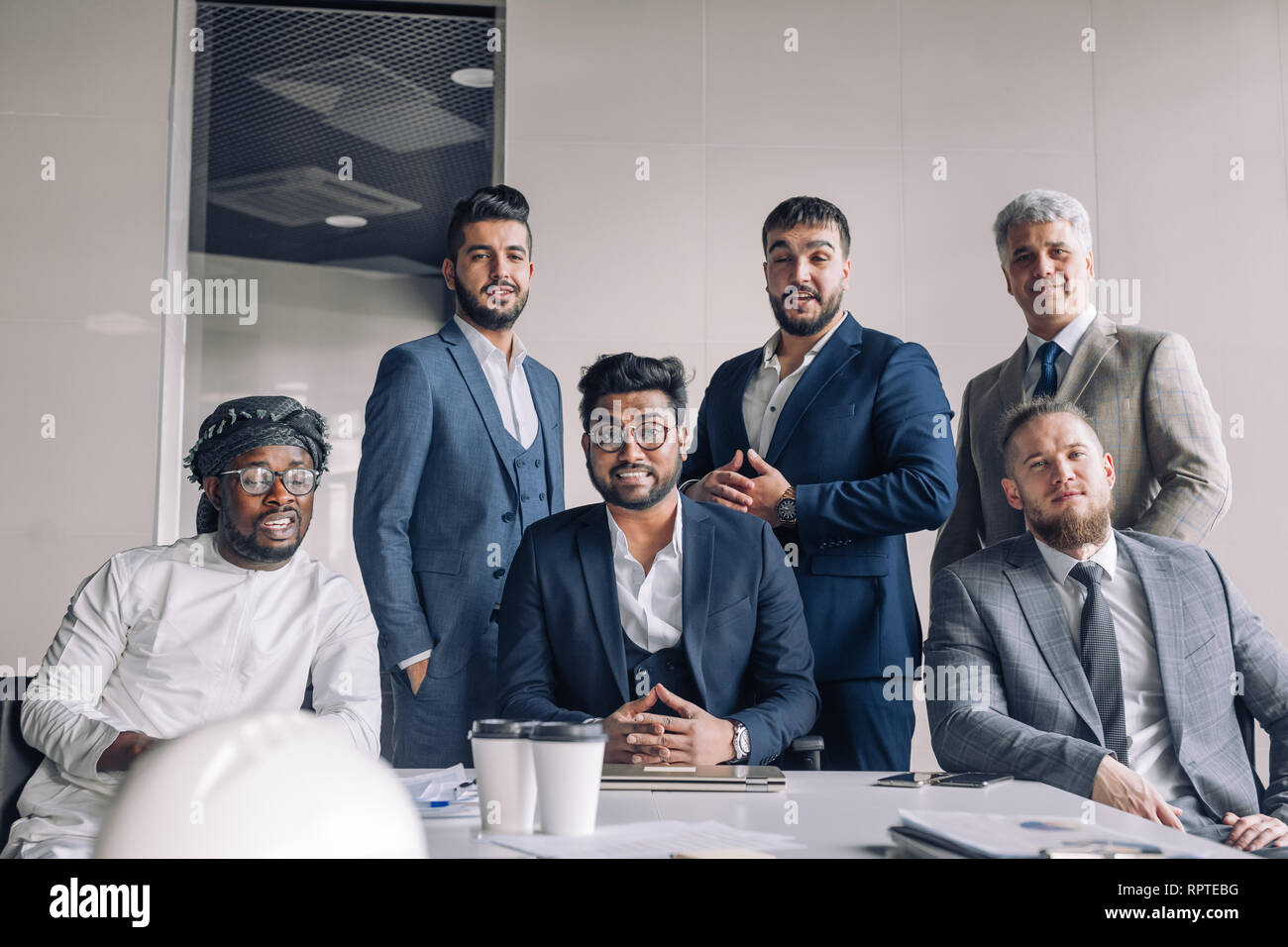 Diverse smiling business men gather at conference table together with ...