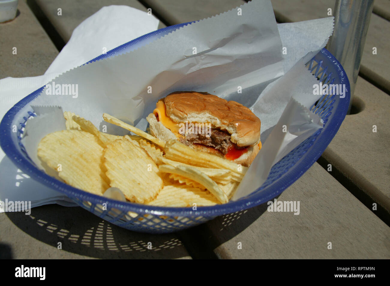 Concession stand burger with a bite out of it and chips in a basket ...