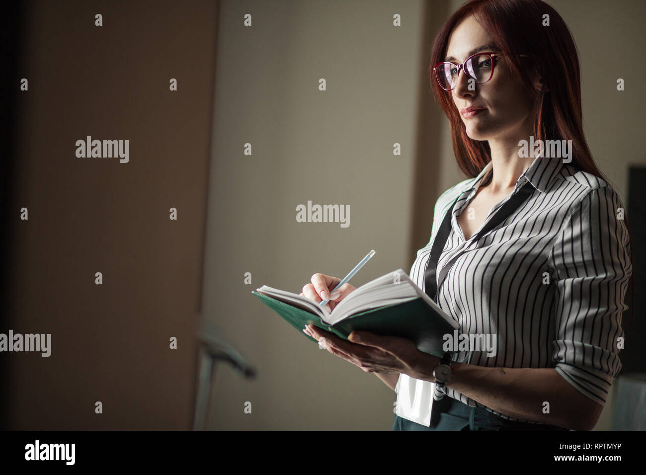 Long haired caucasian business lady in striped silk shirt is creating ...