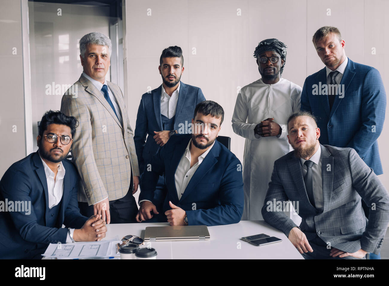 Diverse serious business men gather at conference table together with ...