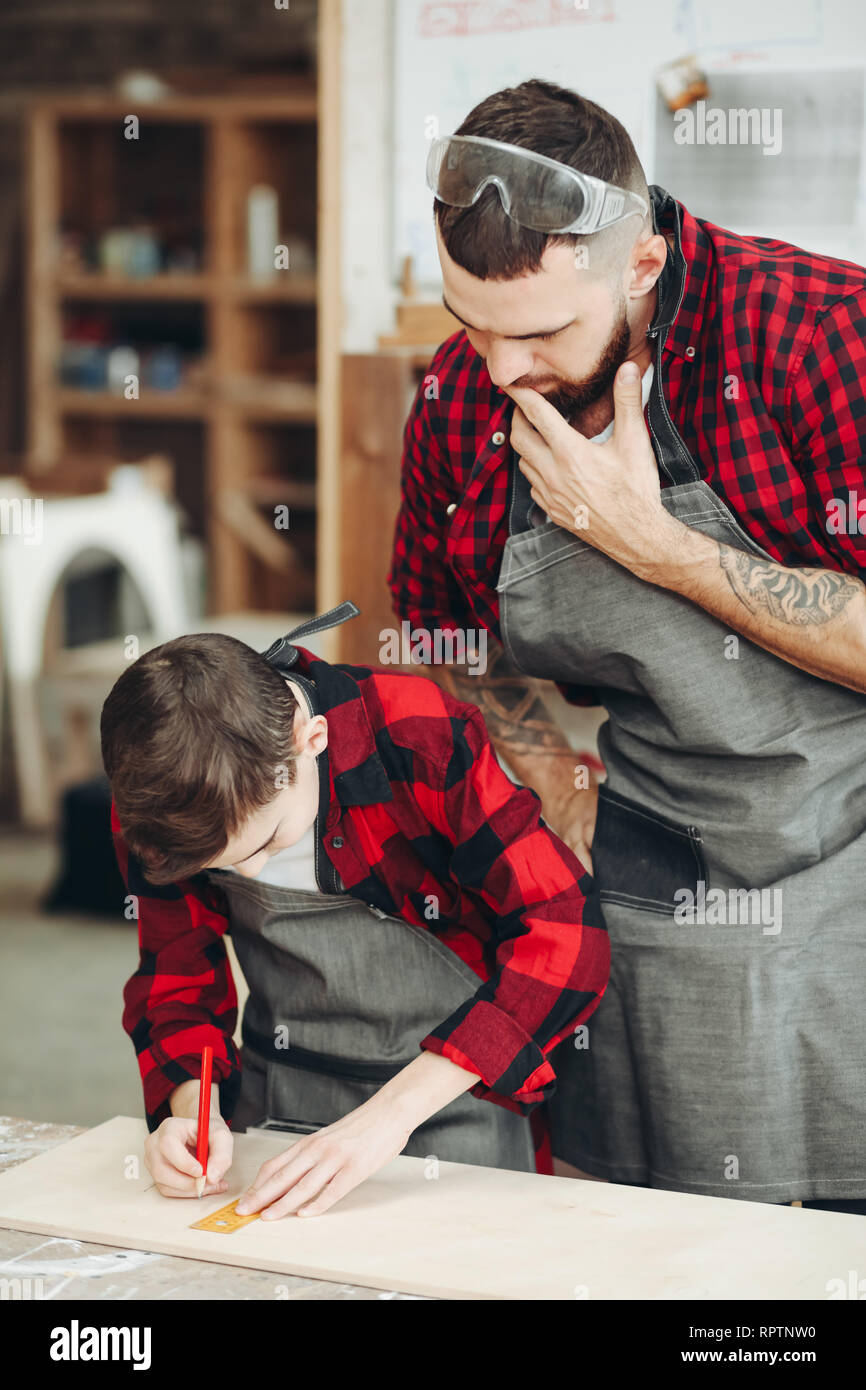Hardworking little boy is busy taking measure and marking of wooden ...