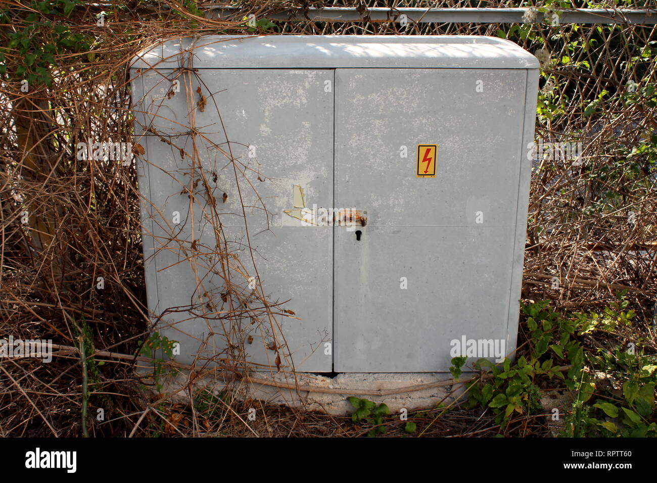 Grey electrical high voltage outdoor box closed with rusted latch ...