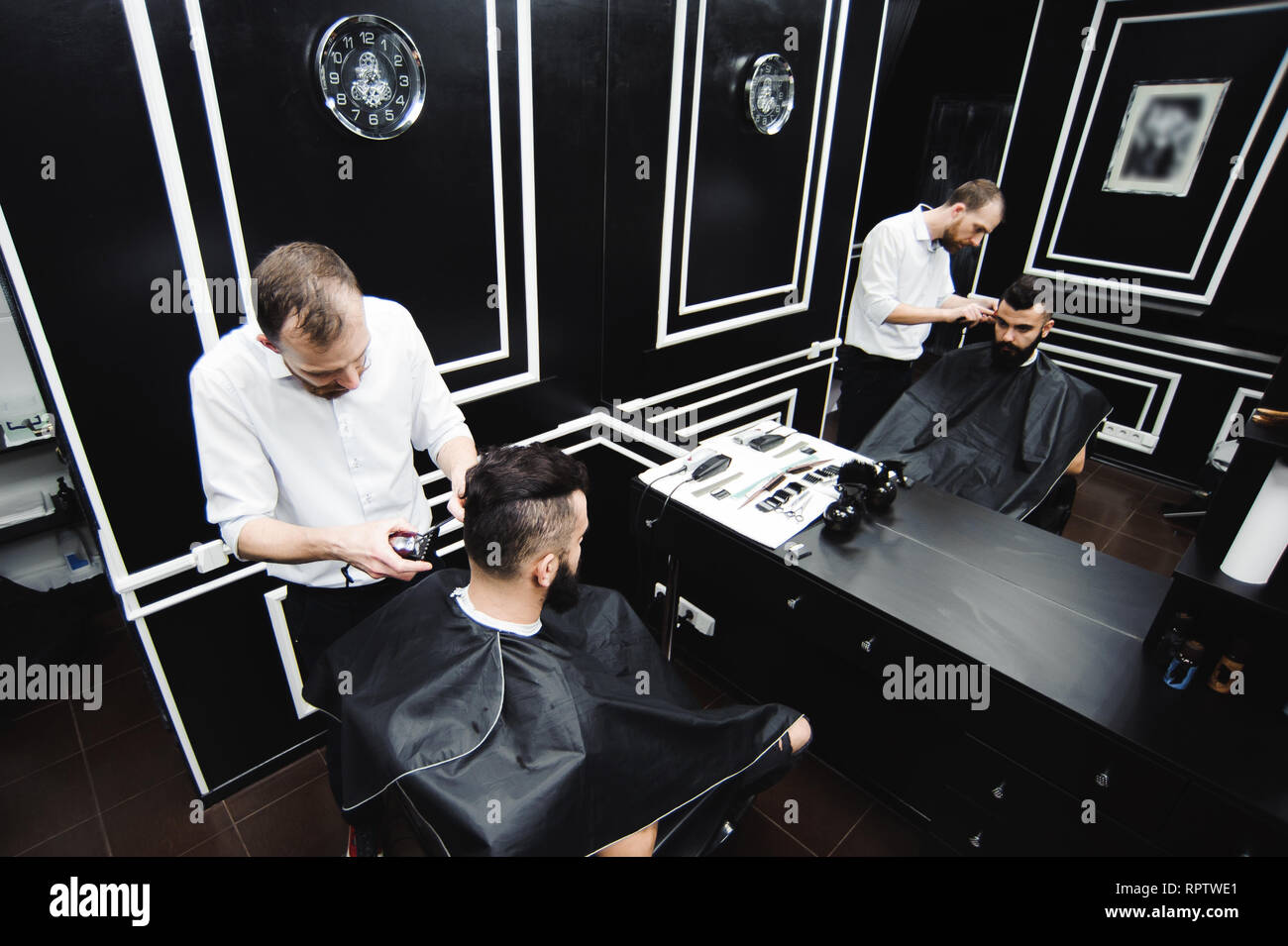 Master cuts hair and beard of men in the barbershop, hairdresser makes ...