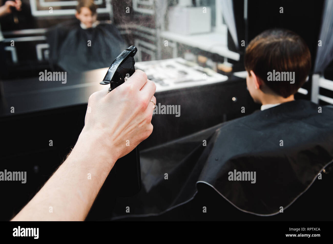 Young handsome barber making haircut of cute boy in barbershop Stock ...
