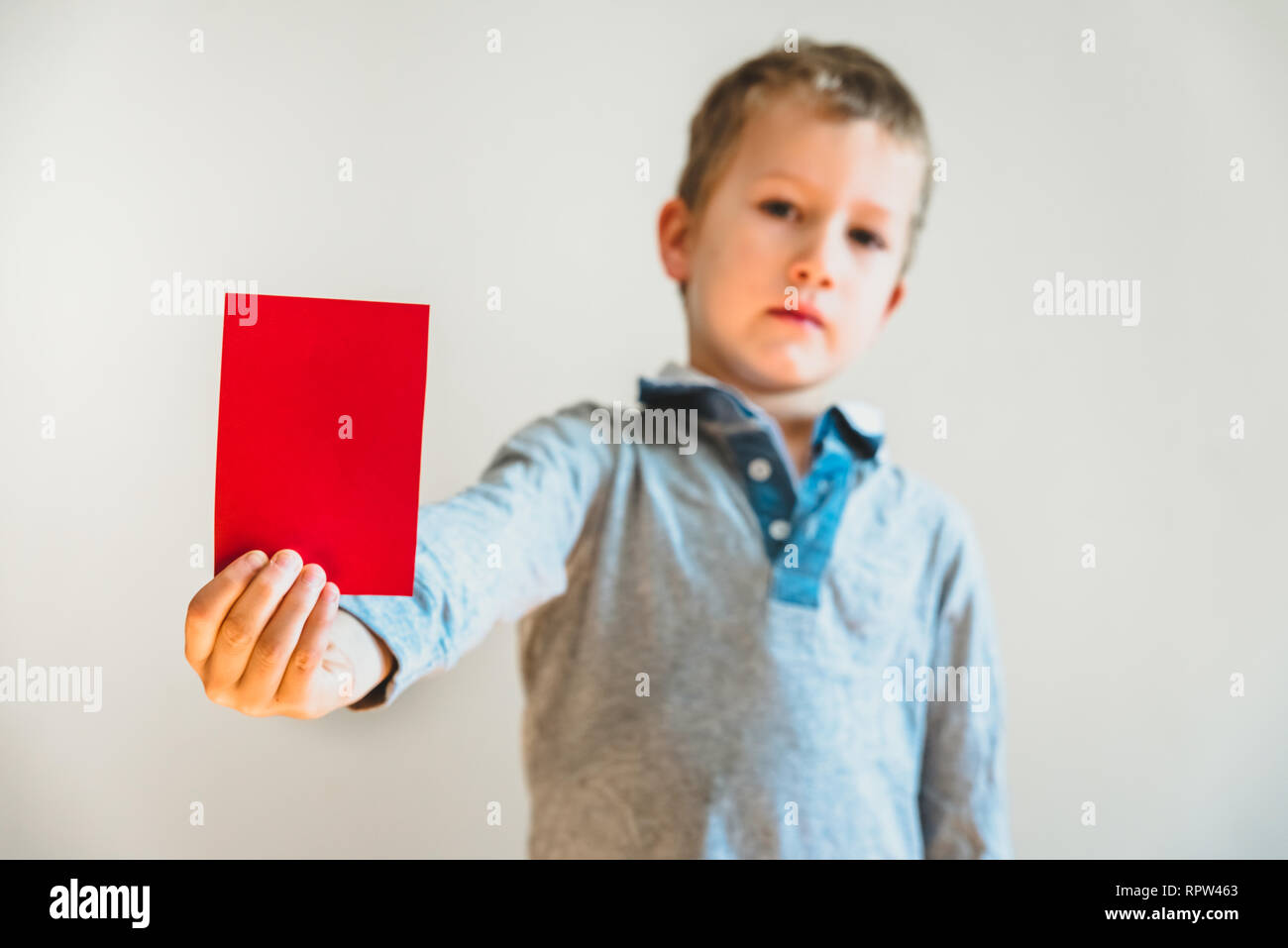 Angry face child showing a red card as a warning, stop bullying concept ...