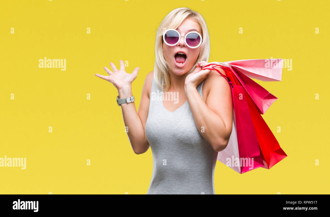 Young beautiful blonde woman shopping holding shopping bags on sales ...