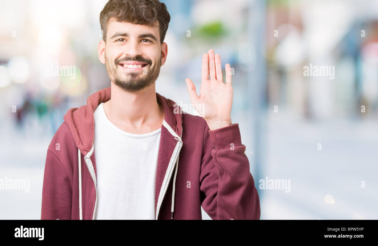 Young handsome man over isolated background Waiving saying hello happy ...