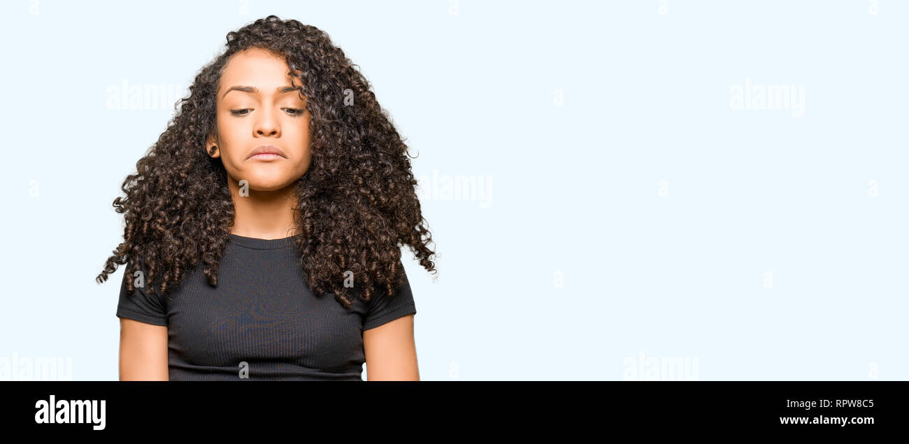 Young beautiful woman with curly hair depressed and worry for distress ...