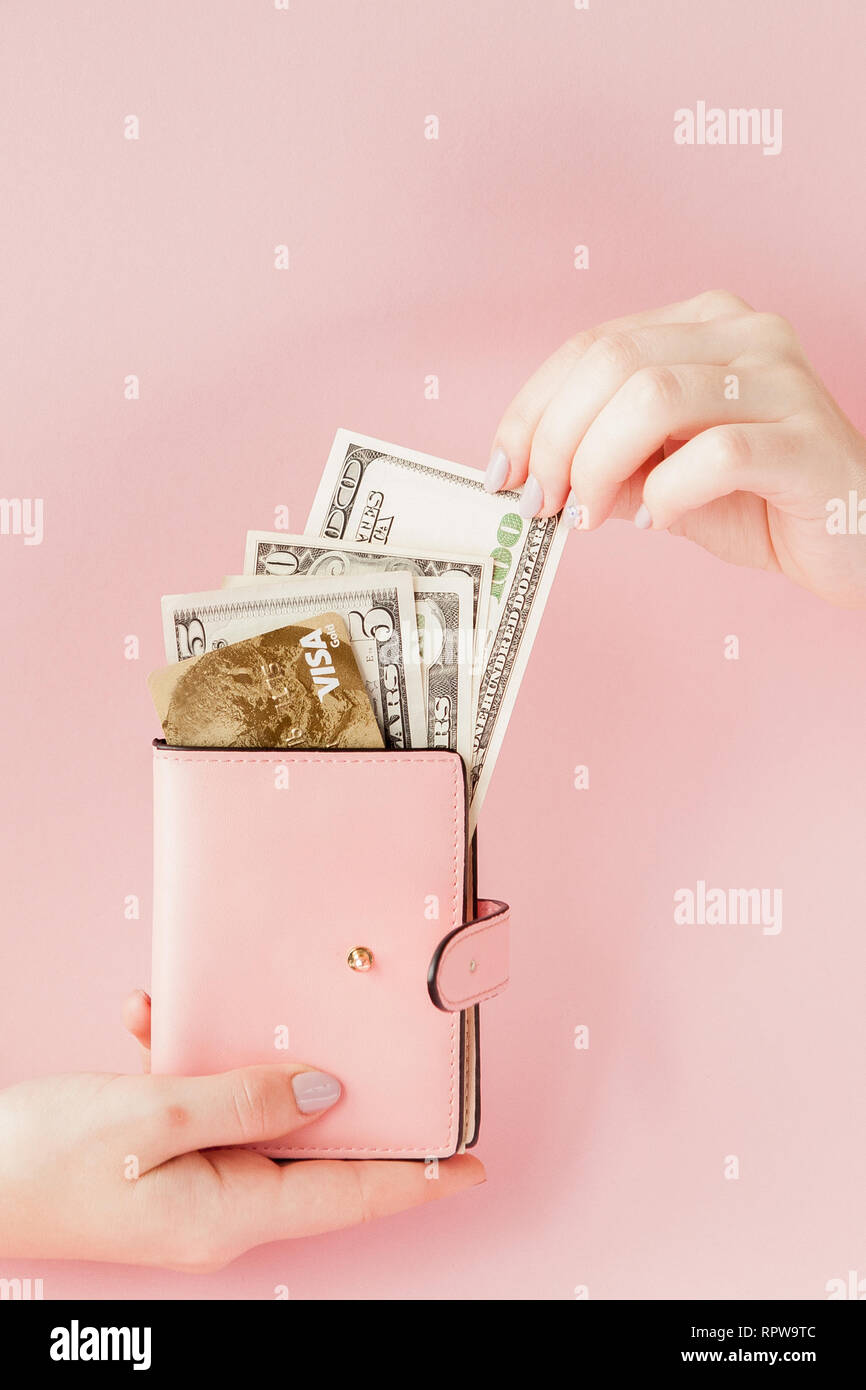 Dollars and pink wallet with credit card in woman's hands on pink ...