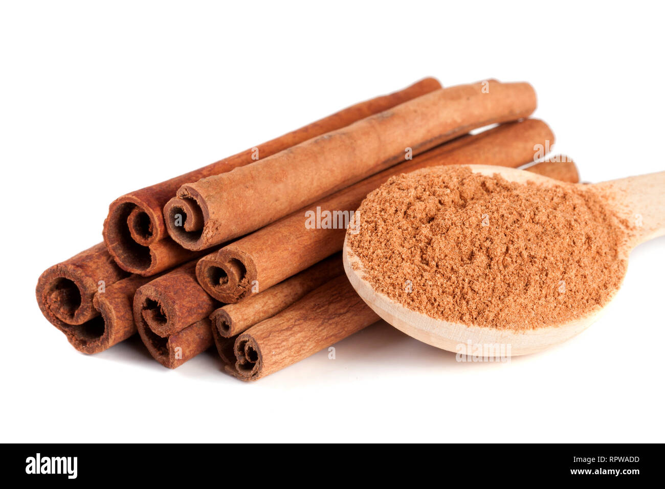 a stack of cinnamon sticks and powder with spoon isolated on white ...