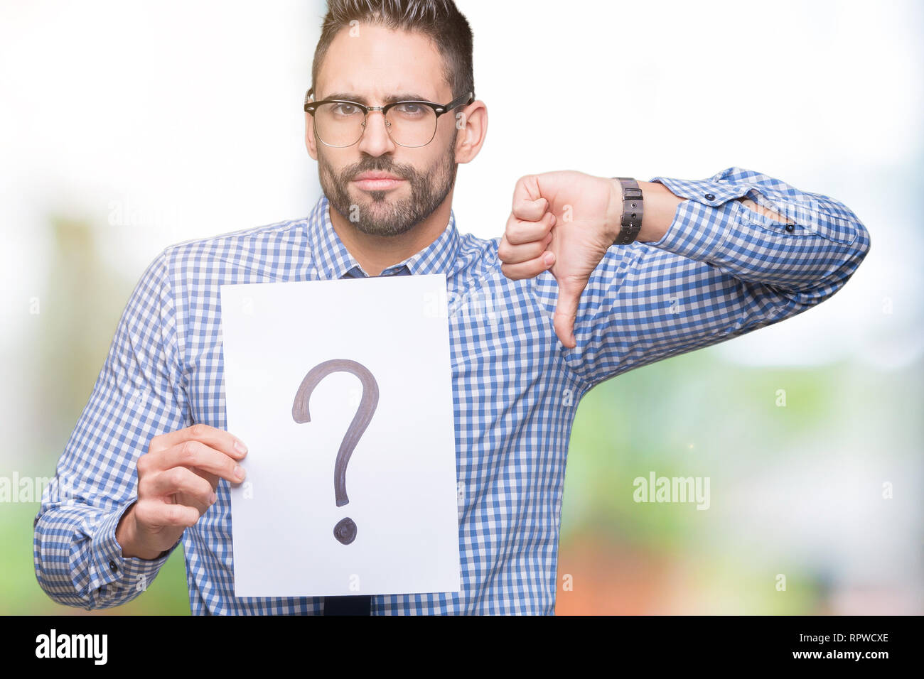 Handsome young business man holding paper with question mark over ...