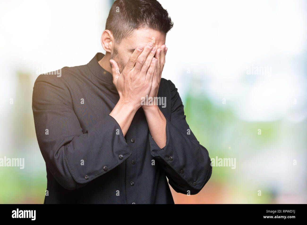 Young Christian priest over isolated background with sad expression ...