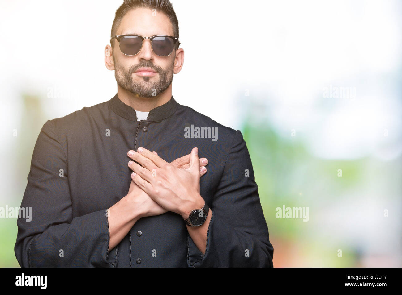 Young Christian priest wearing sunglasses over isolated background ...