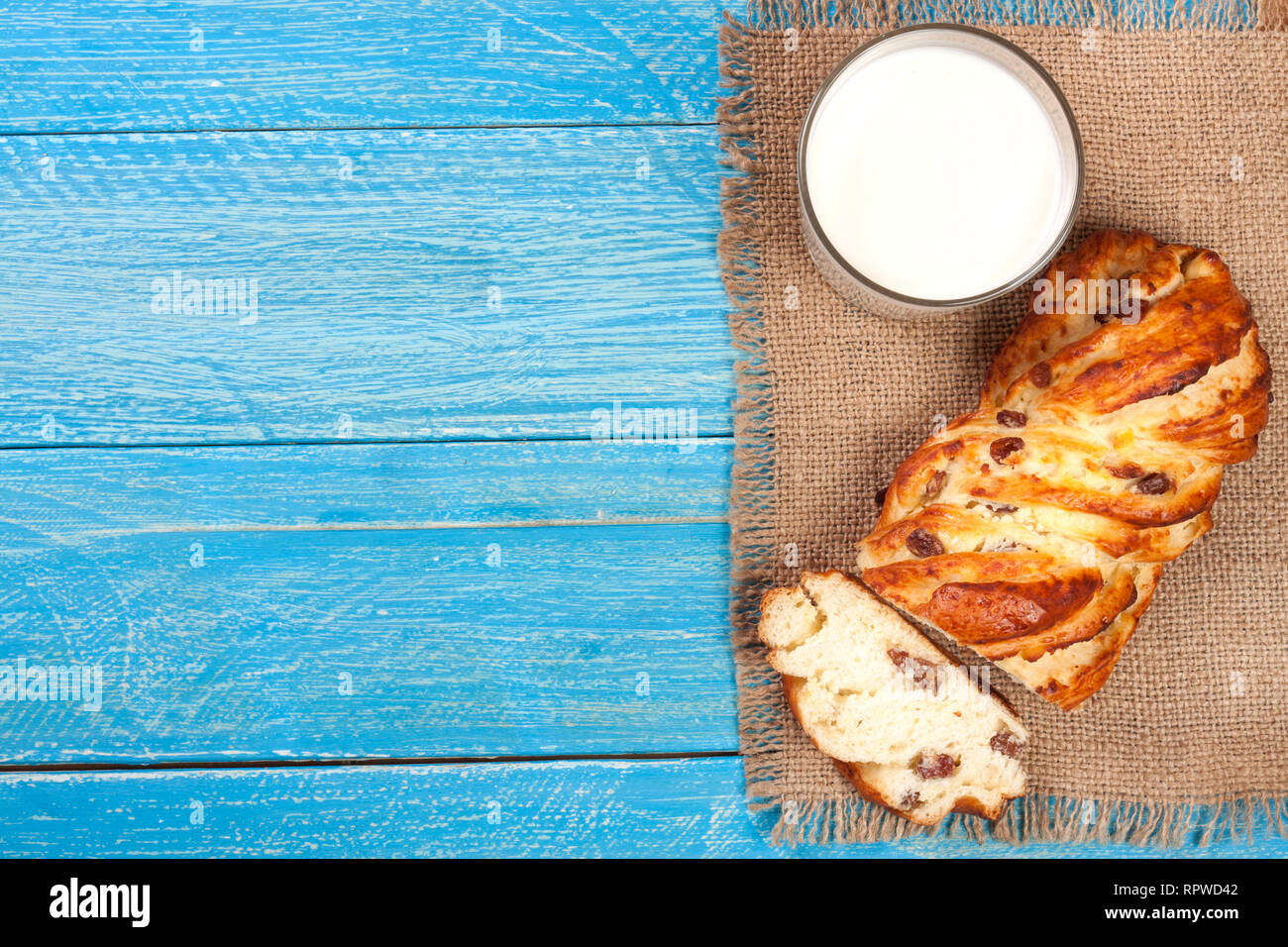 glass of milk with a loaf of bread on a blue wooden background with ...