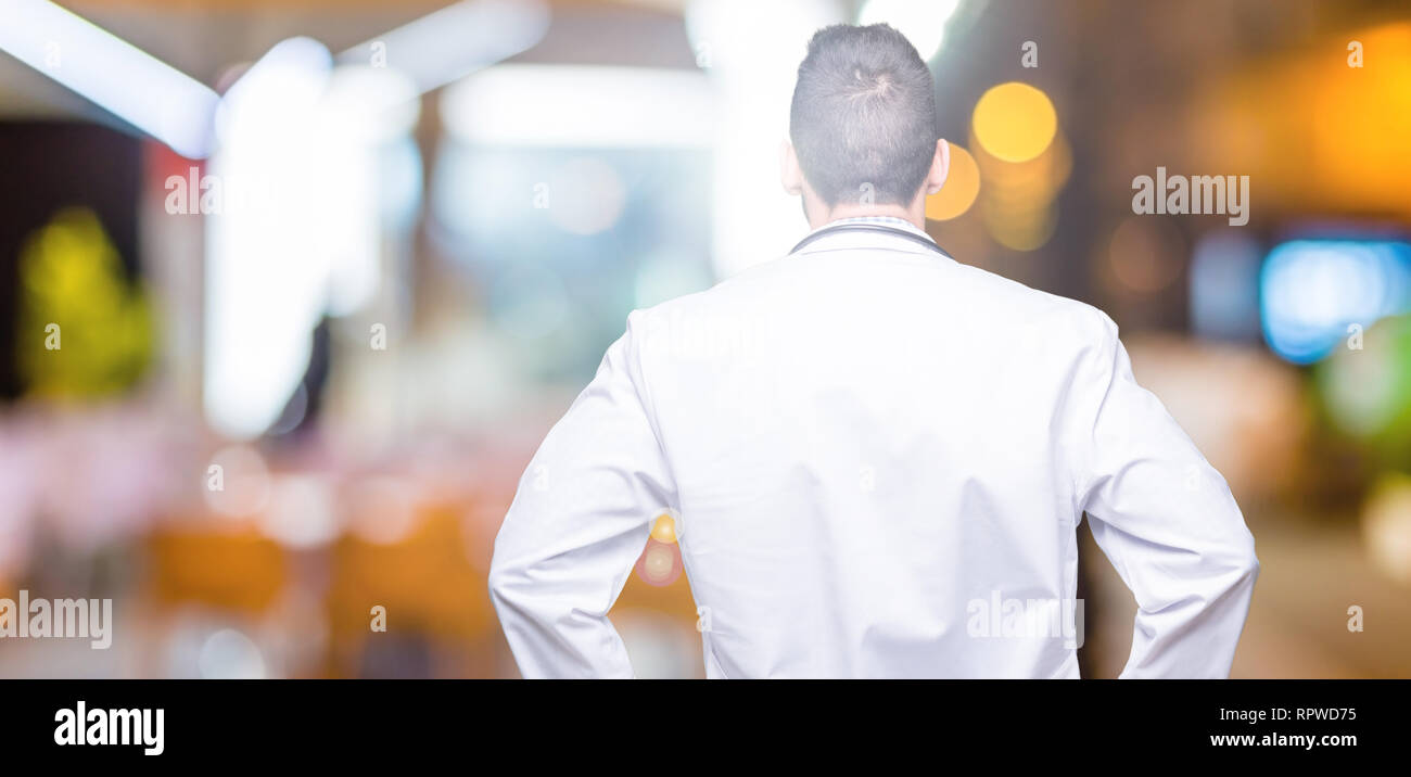 Handsome young doctor man over isolated background standing backwards ...