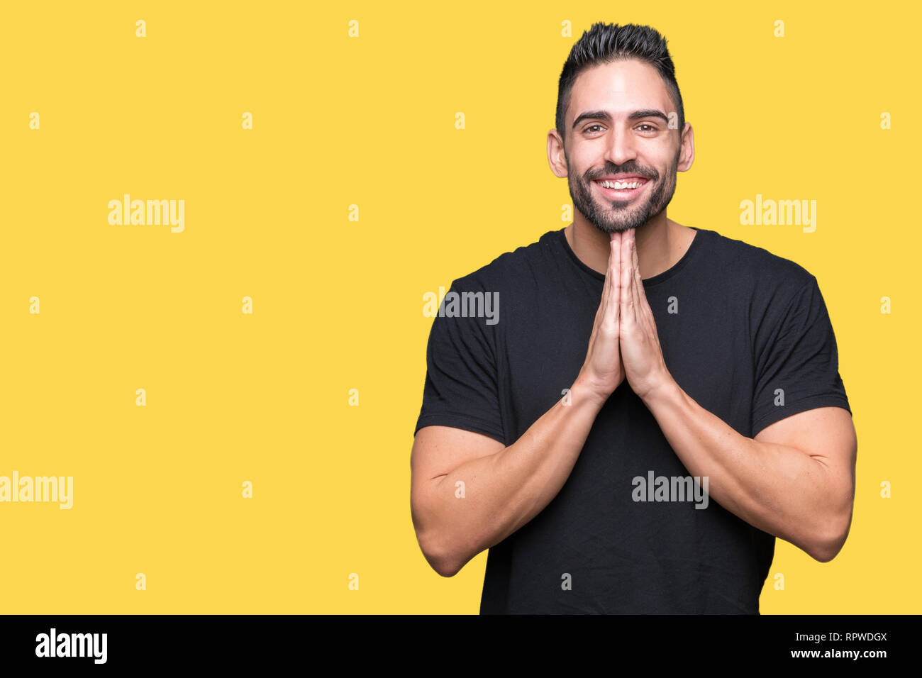 Young handsome man over isolated background praying with hands together ...