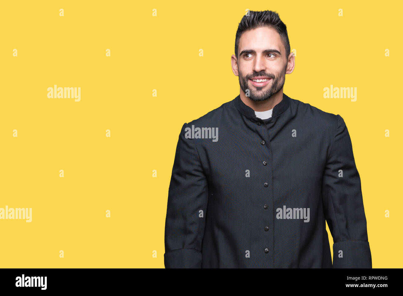 Young Christian priest over isolated background smiling looking side ...