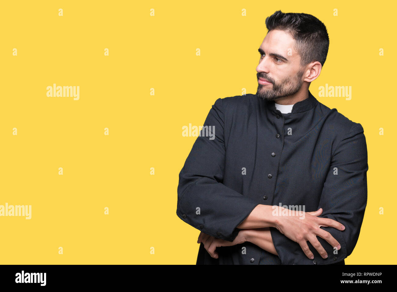 Young Christian priest over isolated background smiling looking to the ...