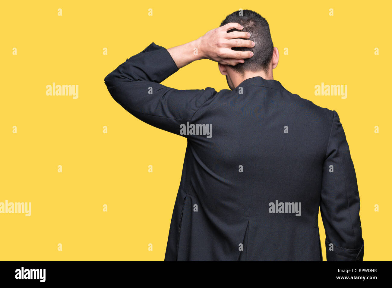 Young Christian priest over isolated background Backwards thinking ...