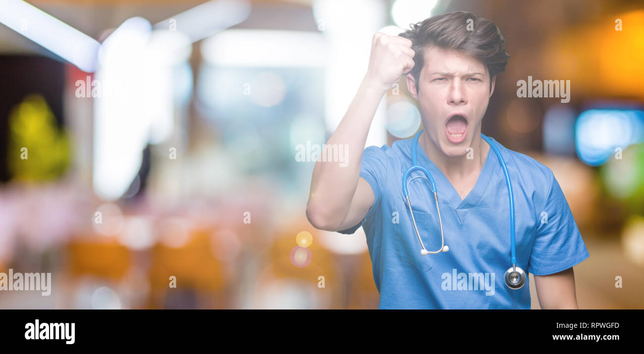 Young doctor wearing medical uniform over isolated background angry and ...