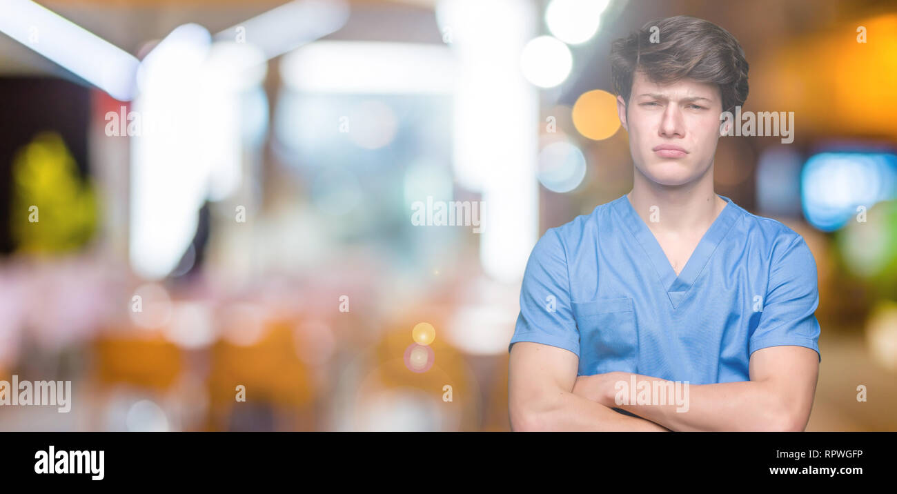 Young doctor wearing medical uniform over isolated background skeptic ...