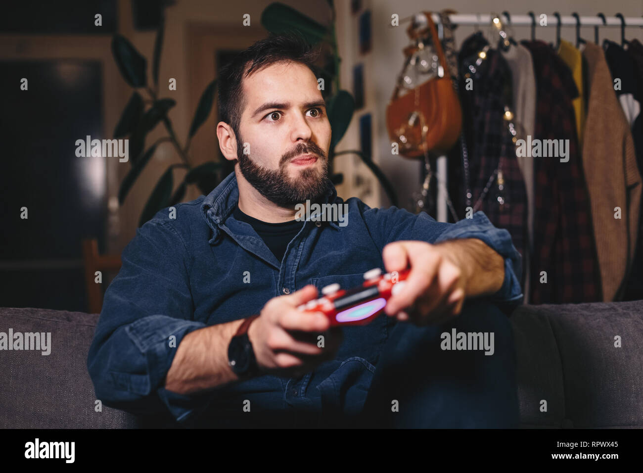 Portrait of a handsome man playing video games in his apartment ...