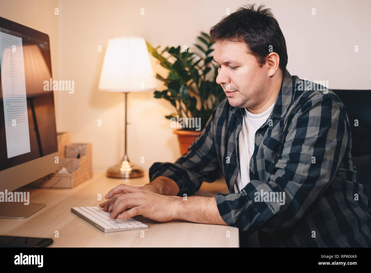 Portrait of a young male writer working from a home office, using a ...