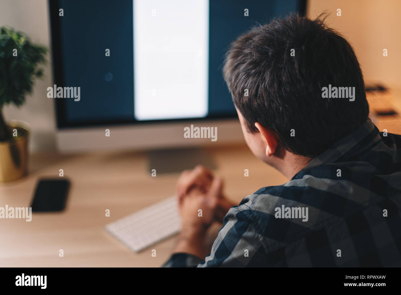 Back view of a young male freelancer working from home office, looking ...