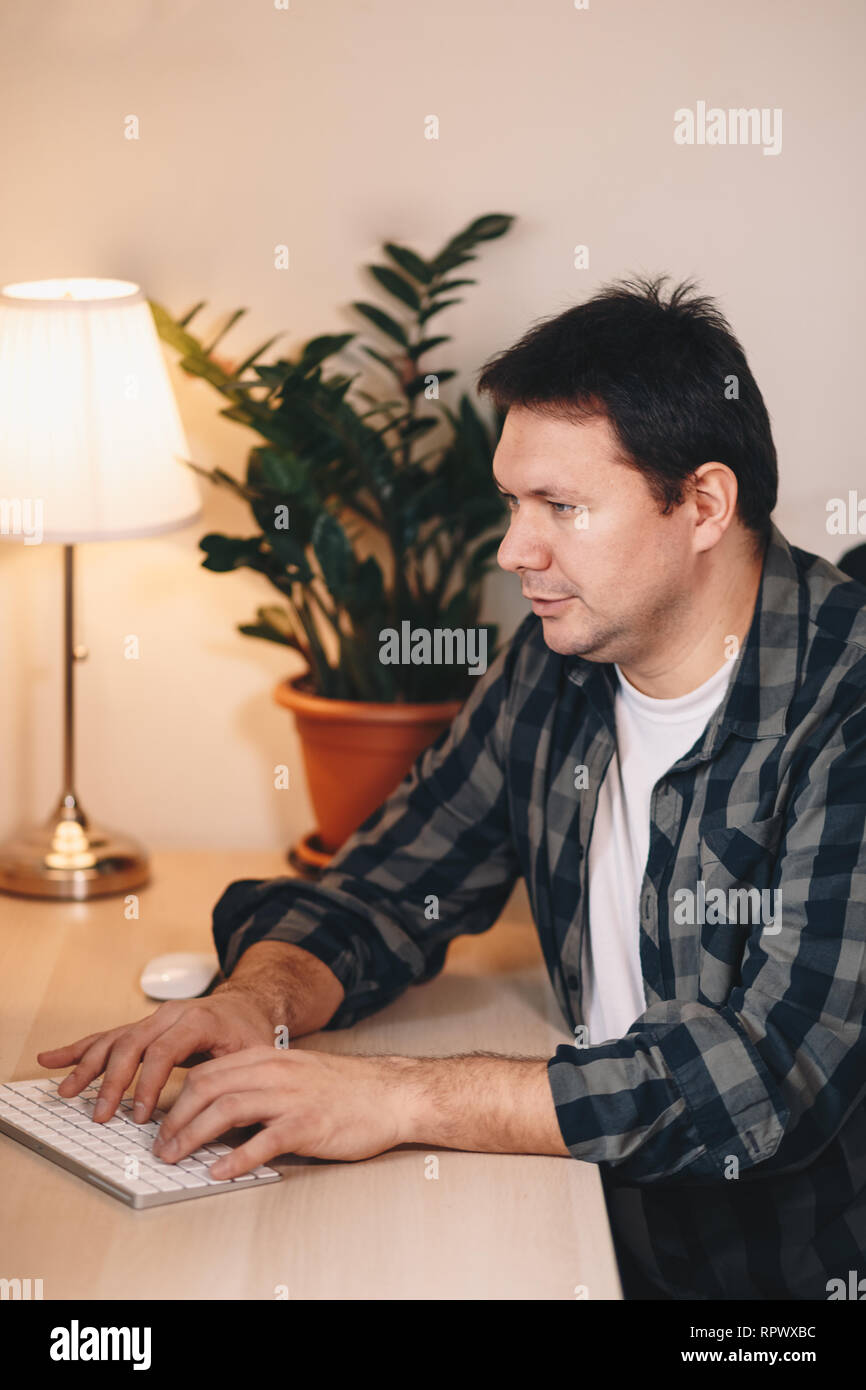 Portrait of a young male writer working from a home office, using a ...
