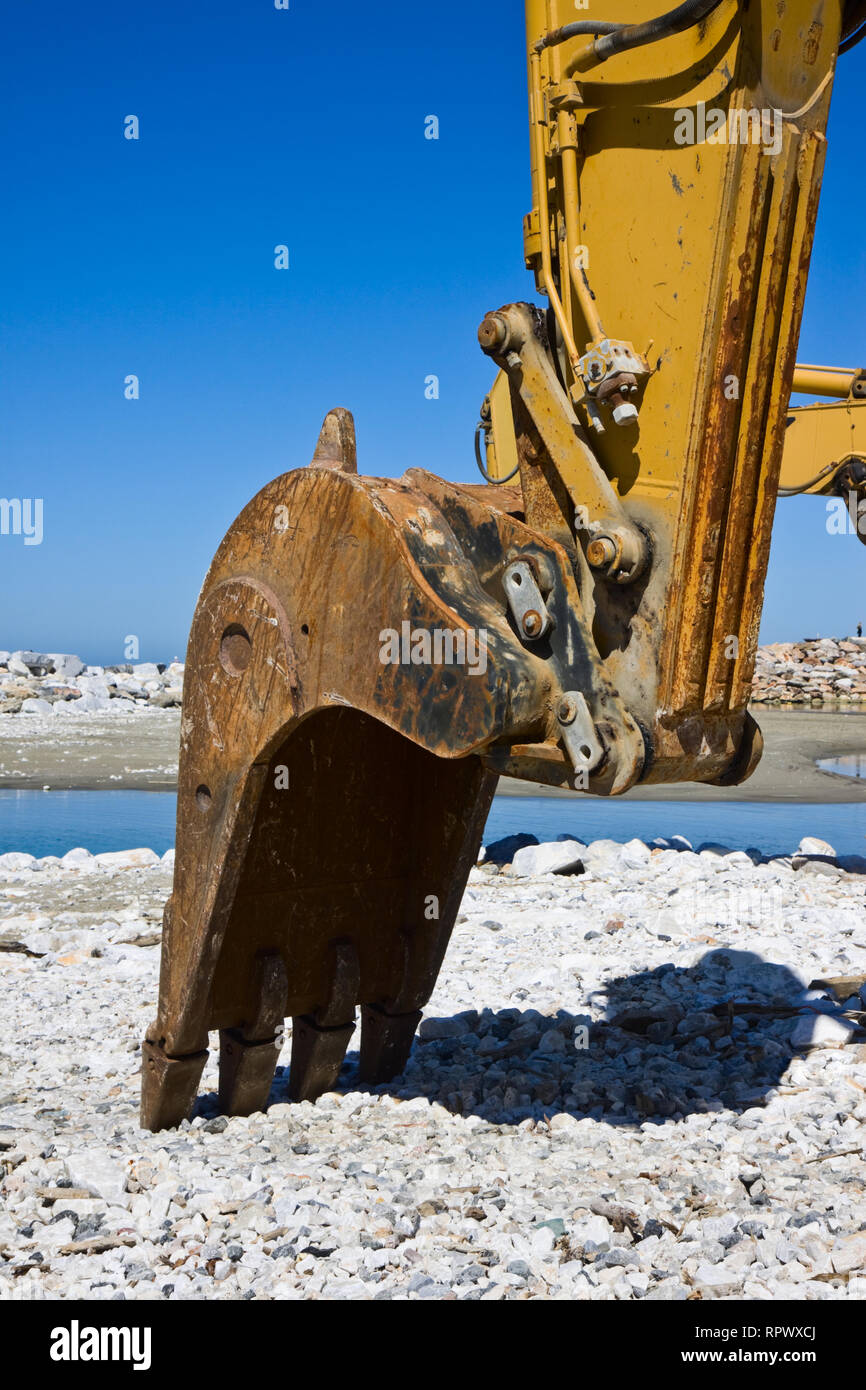 Diggers on the seashore building a breakwater Stock Photo - Alamy