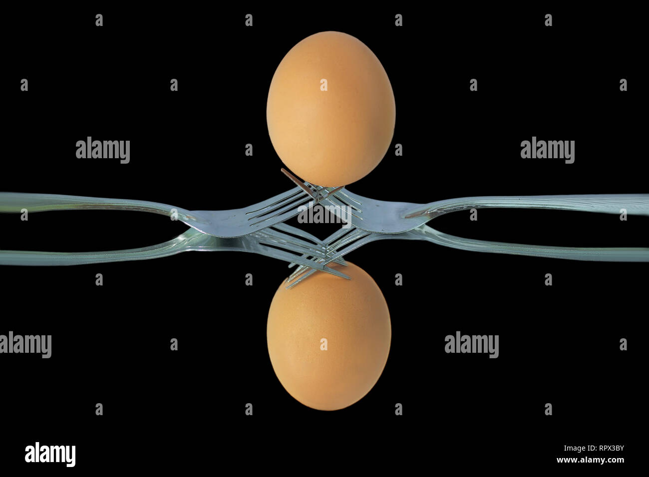 Egg balancing on two forks Stock Photo - Alamy