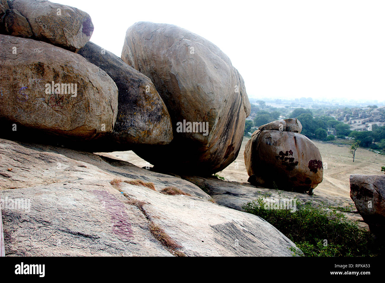 Round rock boulders resting on slope of rock surface at Jatayu Theme ...