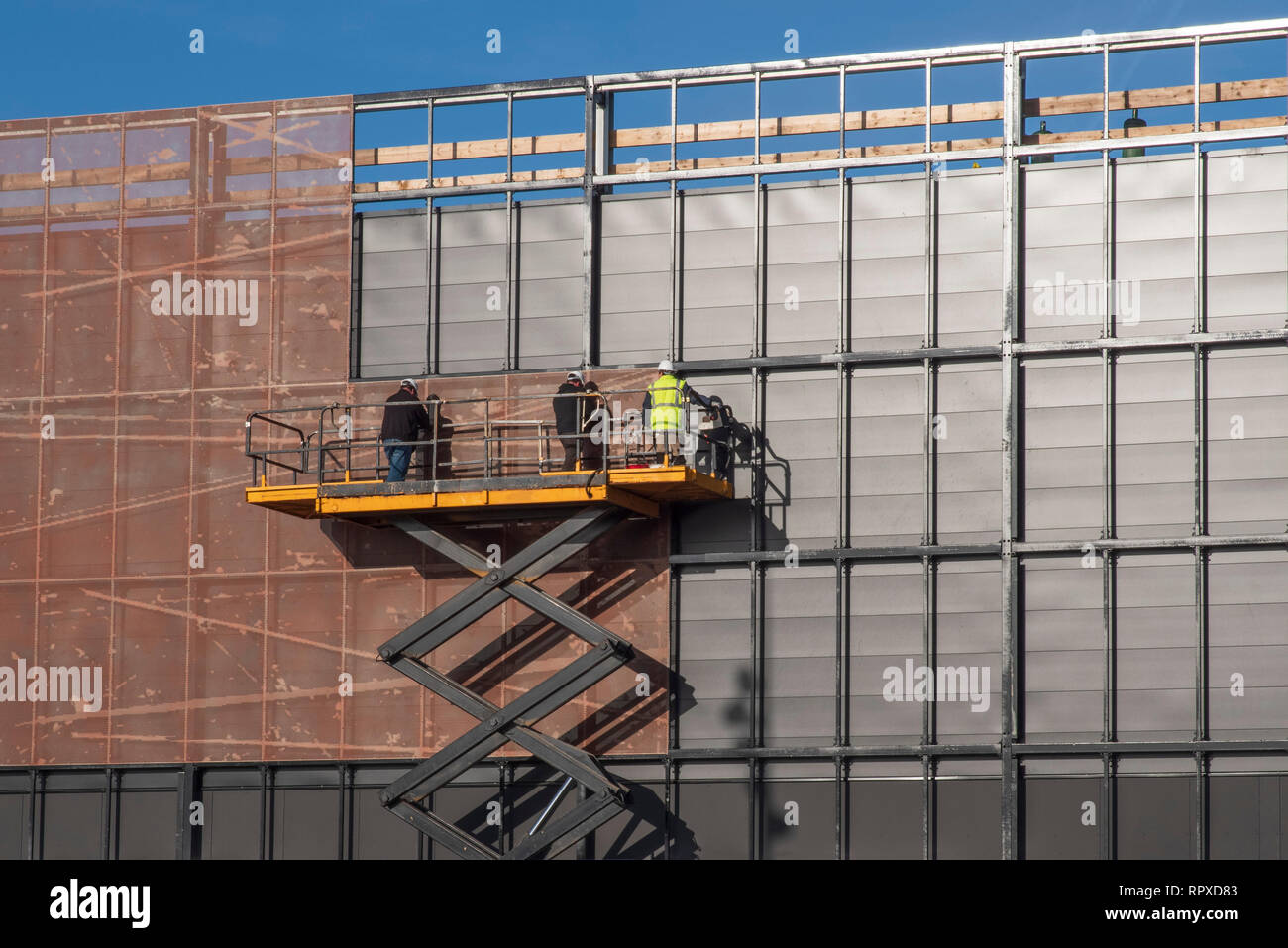 Men on scaffolding build an industrial building façade Stock Photo - Alamy