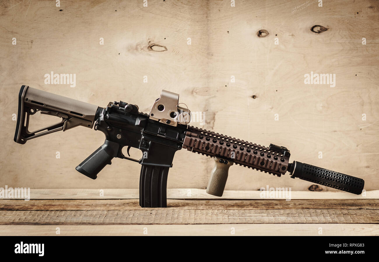 black assault rifle on a light wooden table Stock Photo - Alamy
