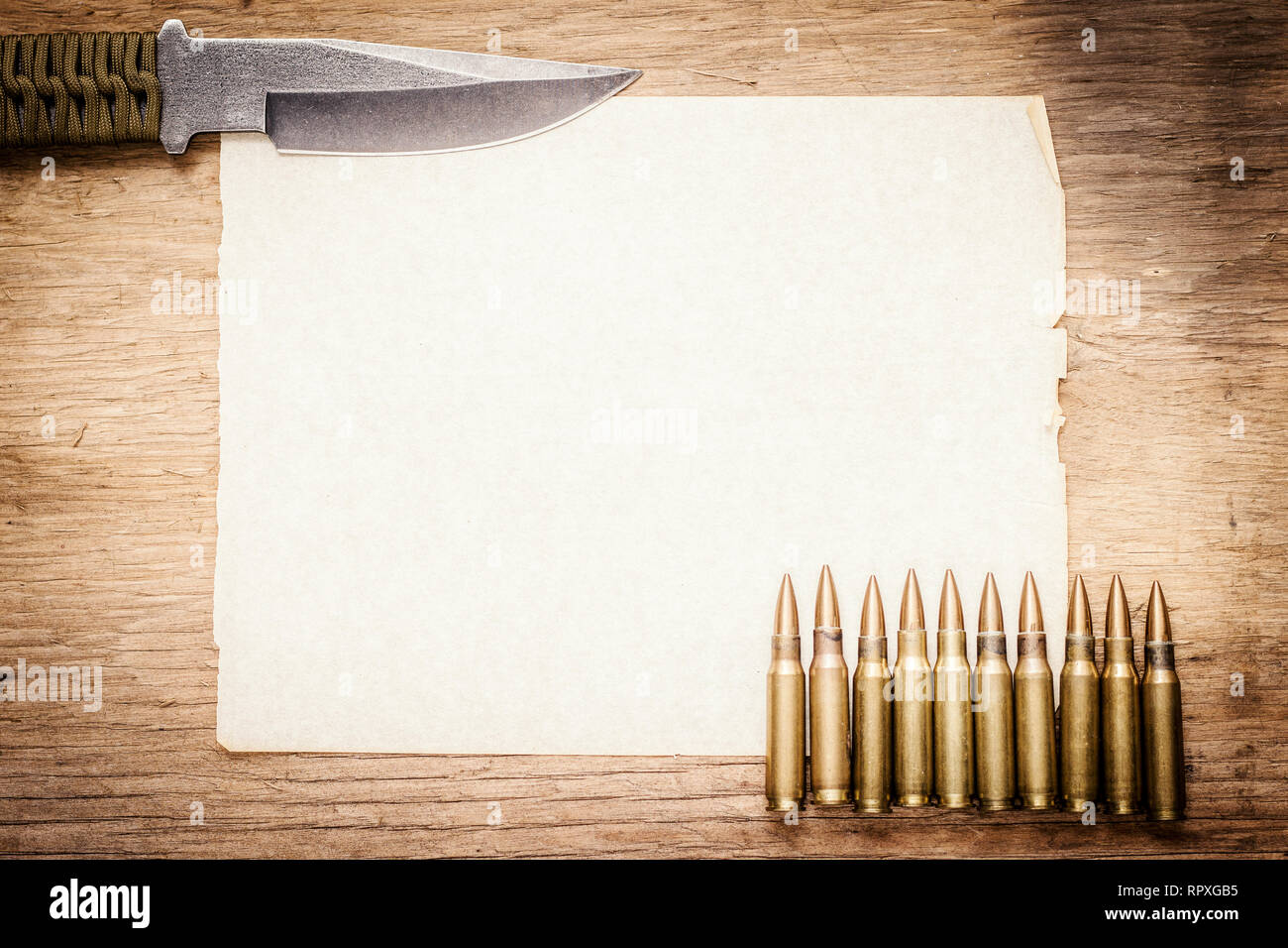 Background. Blank paper, knife and bullets on an old wooden table Stock ...