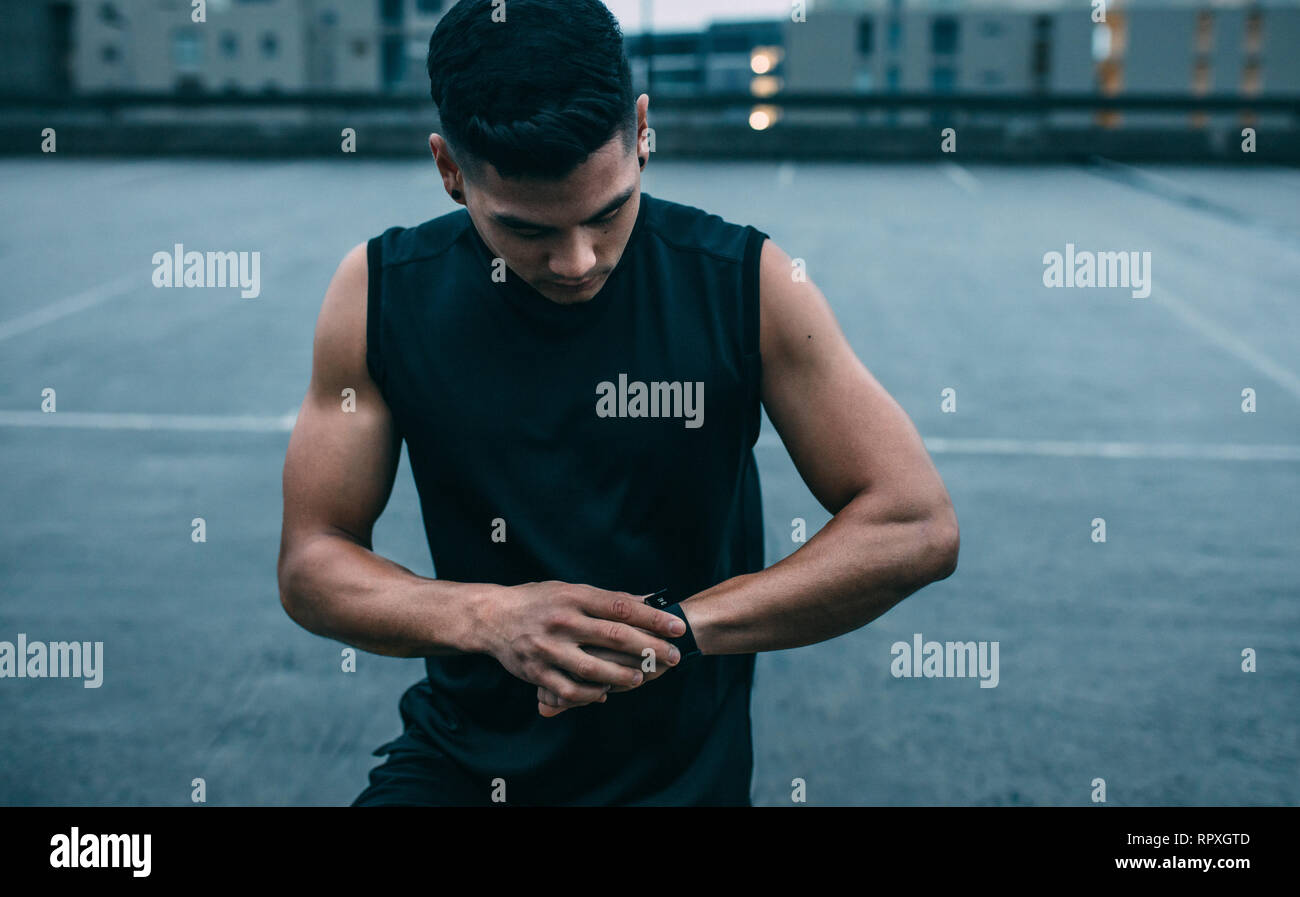 Muscular man checking his performance on fitness app on his smart watch ...