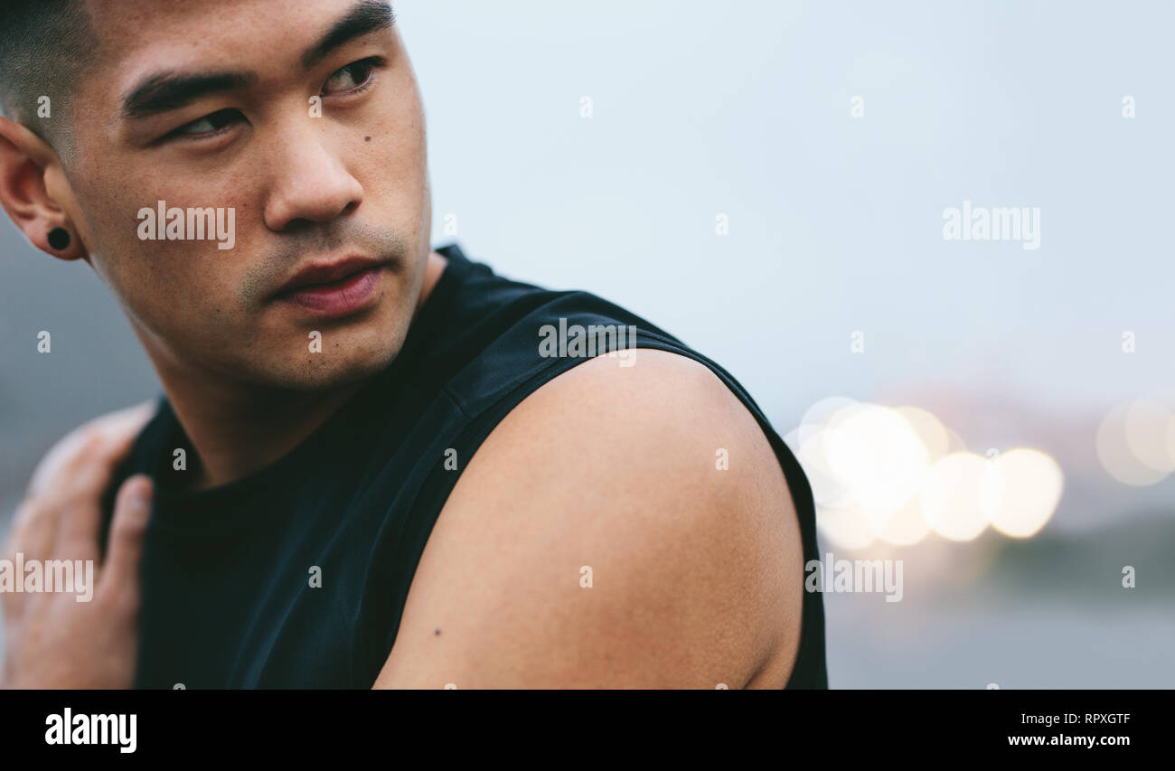 Close up shot of fit young man with muscular build standing outside and ...